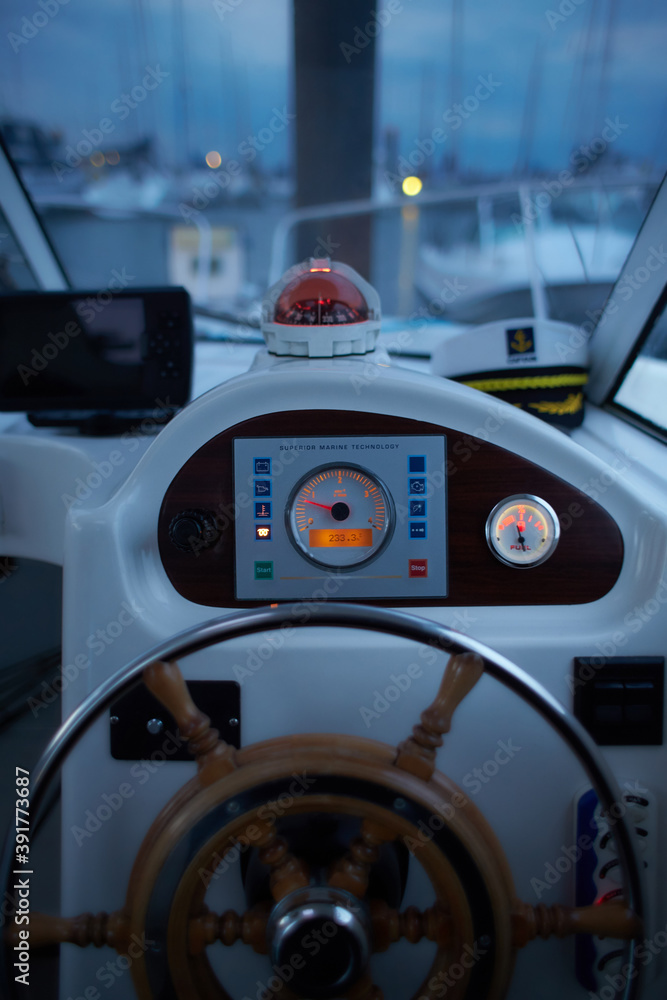 A big compass on a boat showing direction and wood steering wheel in ...