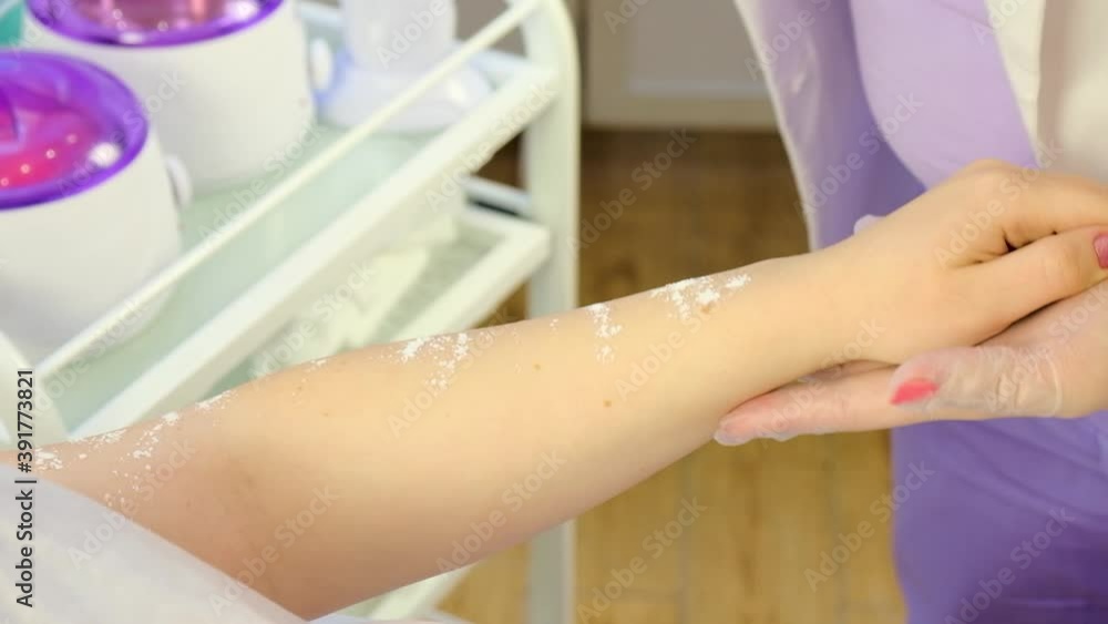 Beautician sprinkles talcum powder on the hand of a young woman. She ...