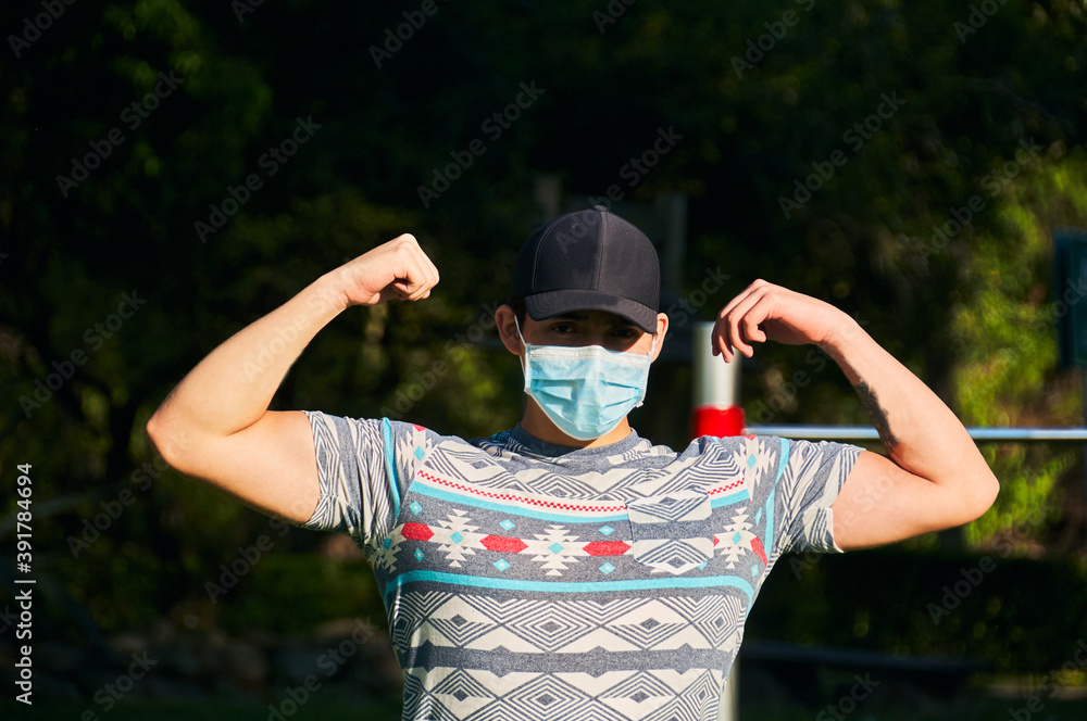 Man wearing a face mask posing showing his muscles after his workout ...