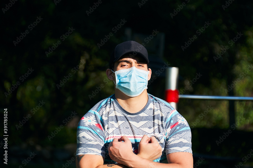Young man wearing a face mask posing showing his muscles after his ...