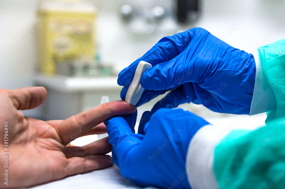 Hands of a nurse with individual protection equipment and patient, in ...