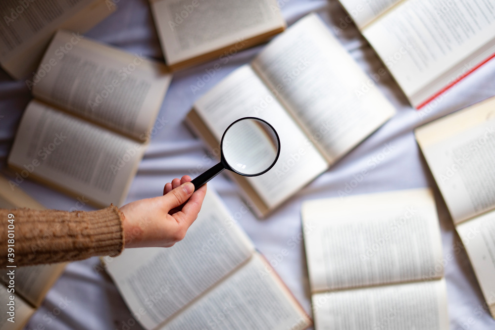 Hand with magnifying glass on top of a background with books. Stock ...