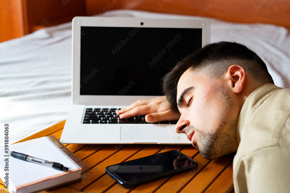 Man sleeping on top of his desk while working. Stock Photo | Adobe Stock
