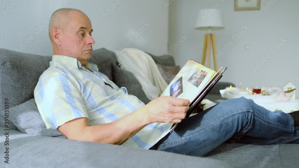 an elderly man looks through an album with his old photographs from ...