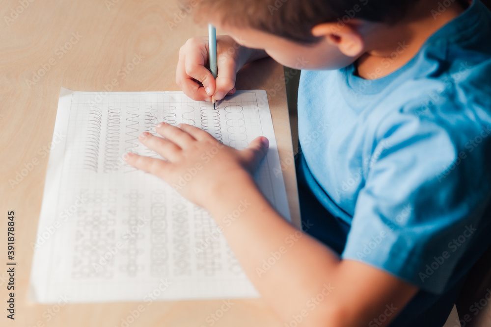 Side view to little boy doing writing exercises. Child writing with ...