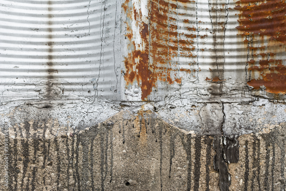 Quonset hut: rusted corrugated metal and concrete with dark drip marks ...
