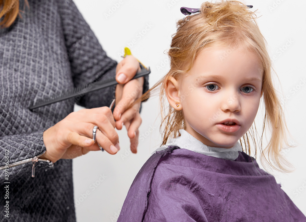 Foto de Hair cutting process. Beautiful little girl at the barber shop ...