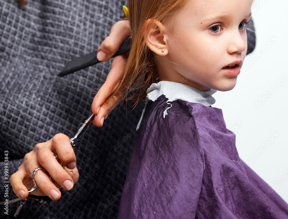 Foto de Hair cutting process. Beautiful little girl at the barber shop ...