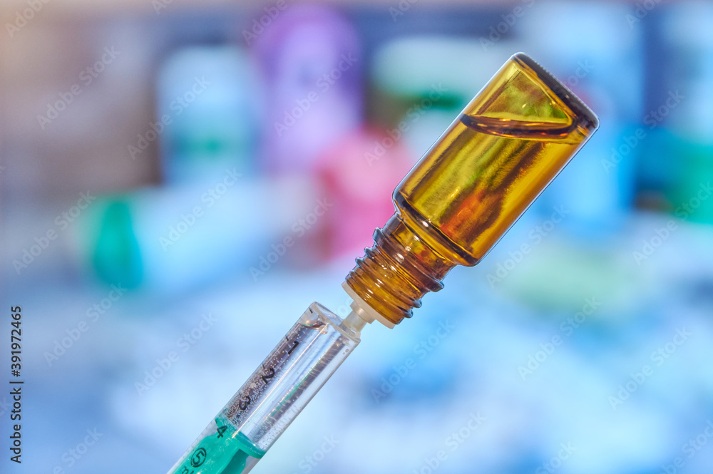Close up of a syringe with vaccine. Close up of a flask with vaccine ...