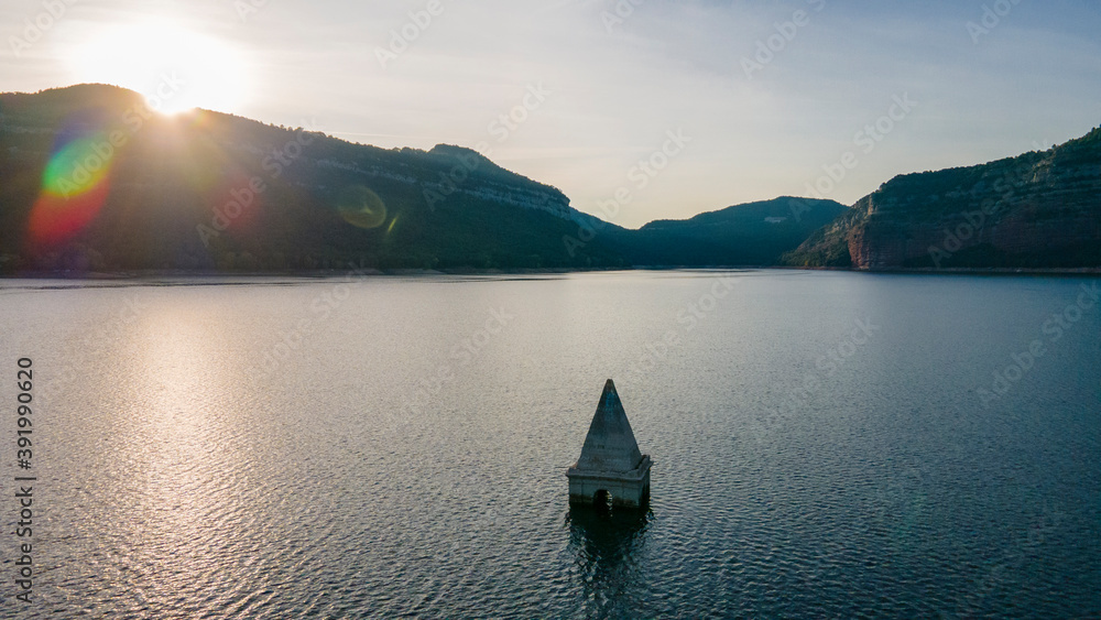 Pueblo sumergido en el pantano al atardecer, se ve la torre de la ...