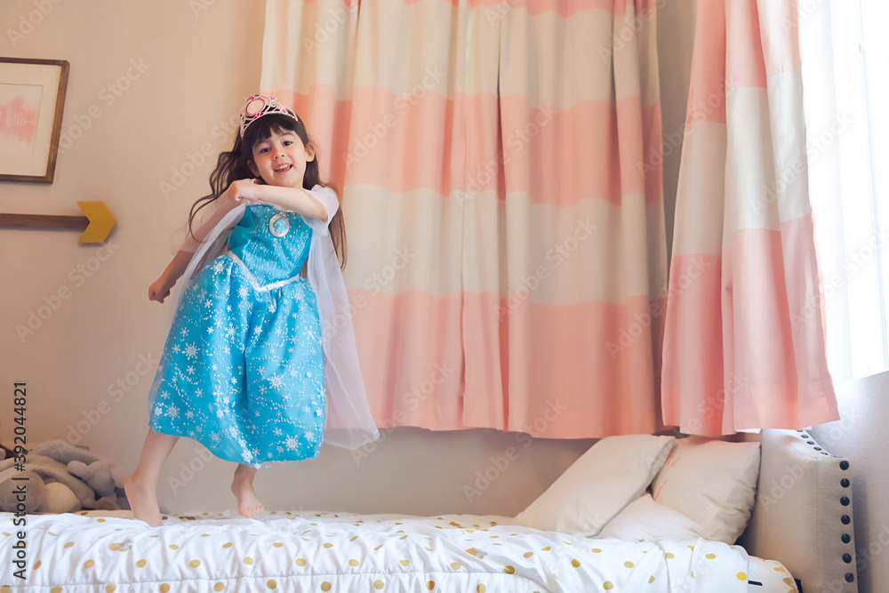 Little girl dressed as a princess dancing and jumping on her bed. Stock ...