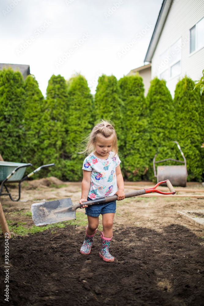 Cute girl holding shovel, digging in backyard of her house. Stock Photo ...