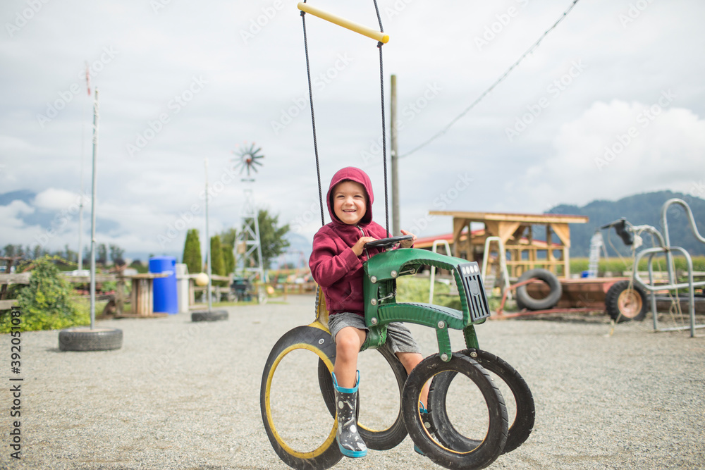 Young boy sits on play ride on tractor at farm. Stock Photo | Adobe Stock