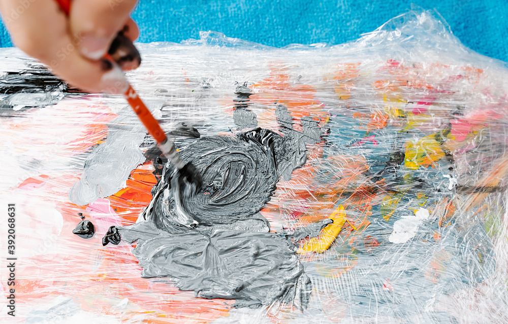 hand with a brush mixing a color painting on a painting palette ...