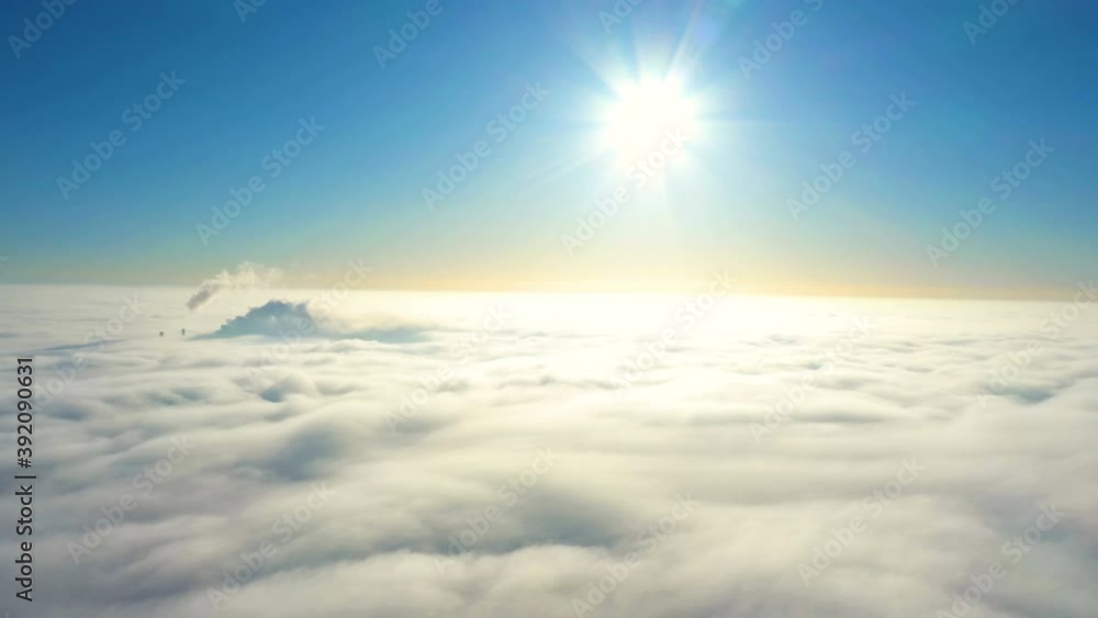 shining sun and clear blue sky while flying above the overcast clouds ...