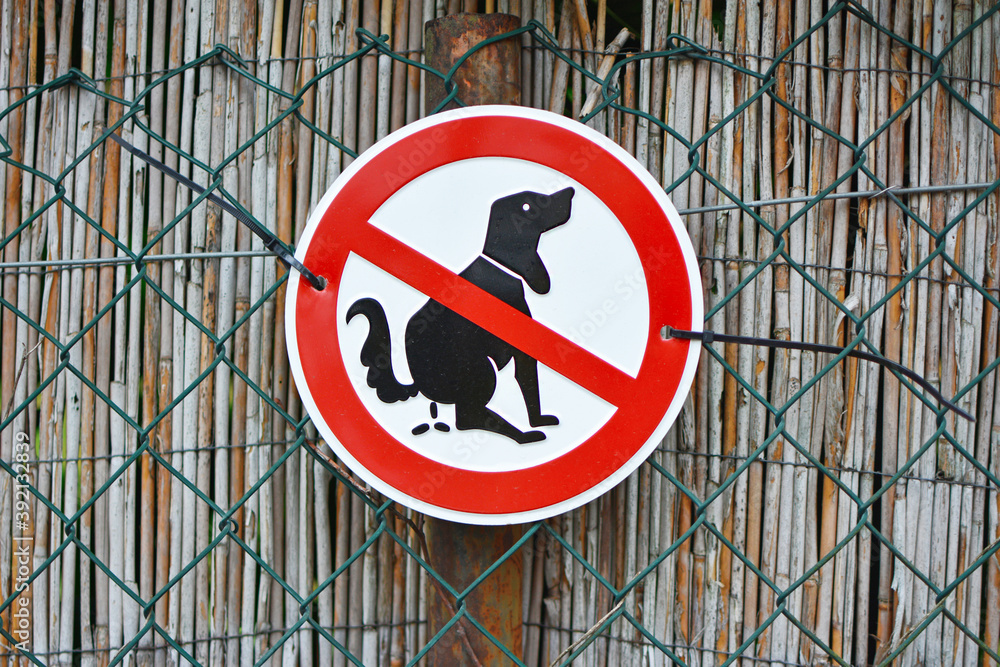Round red and white sign with silhouette of crossed out pooping dog ...