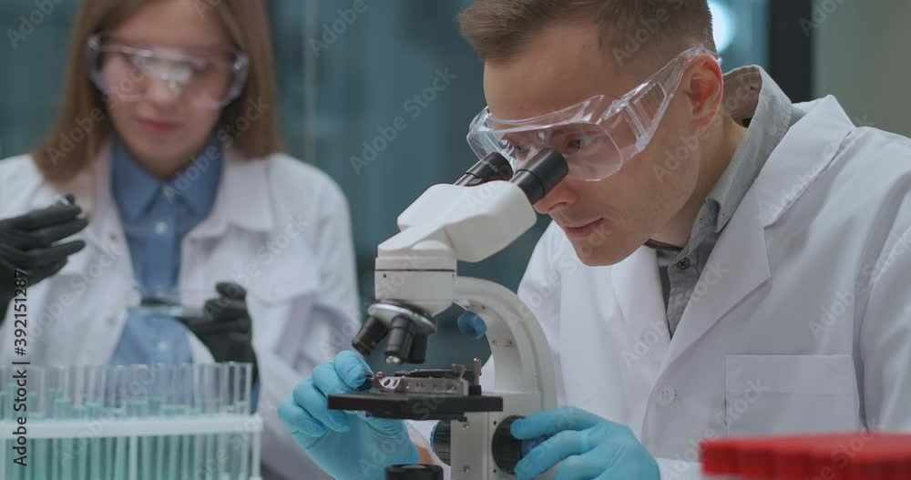 pair of scientists is working in crime lab, man is viewing evidence in ...