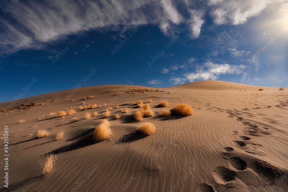This epic image show a unique perspective of a tall sand dune with blue ...