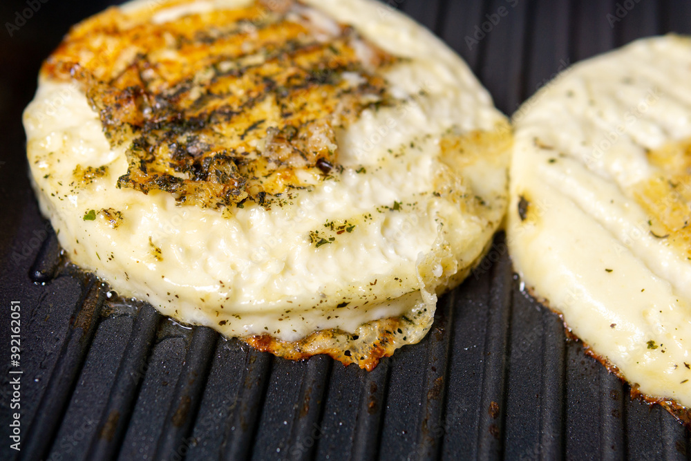 delicious pieces of halumi cheese cooking on a hot iron stove with ...