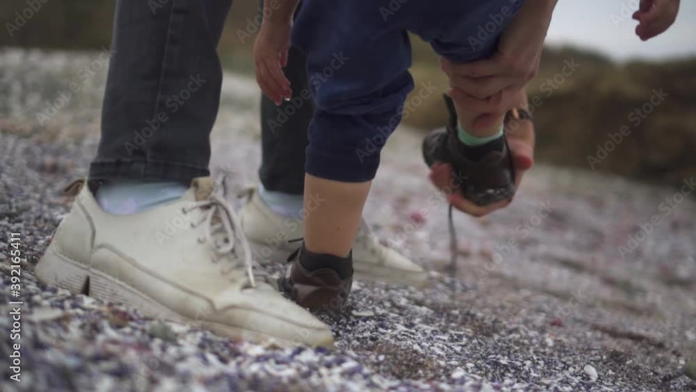 Mom Taking Off The Shoes And Socks Of Her Little Girl At The Beach ...