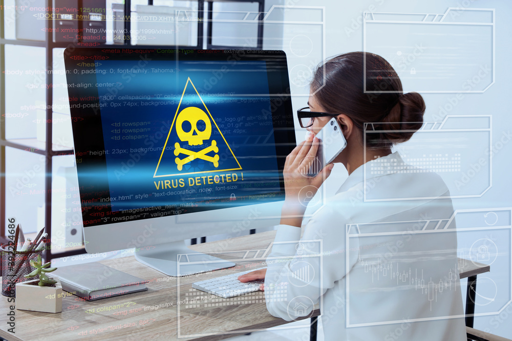 Office worker in front of computer with warning about virus attack on ...