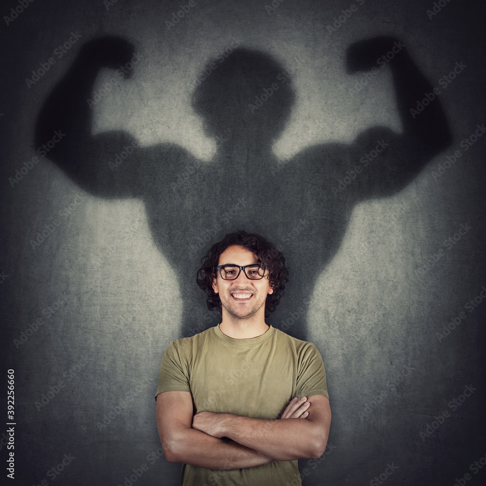 Confident young man shadows transforms into a muscular person on the ...