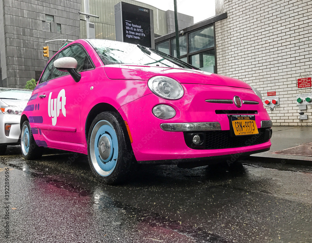 Fiat 500 painted pink and carrying a Lyft logo. Stock Photo | Adobe Stock