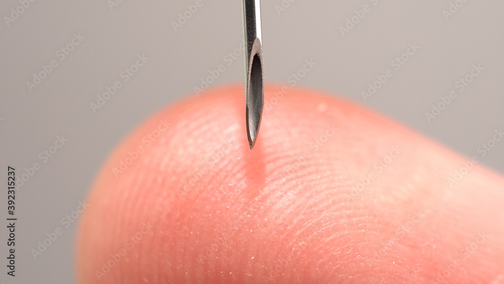 Finger touching medical syringe needle. Macro close up. Trypanophobia ...