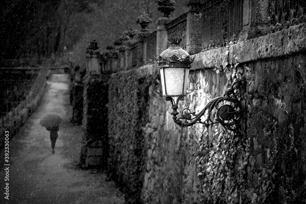 Primer plano de un farol en el muro de un parque y con la silueta de ... Primer plano de un farol en el muro de un parque y con la silueta de ...
