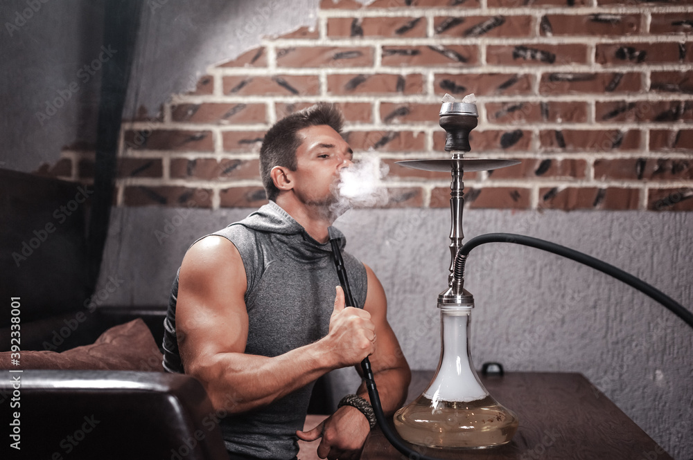 Sexy man enjoy aromatic shisha in nightclub. Stock Photo | Adobe Stock