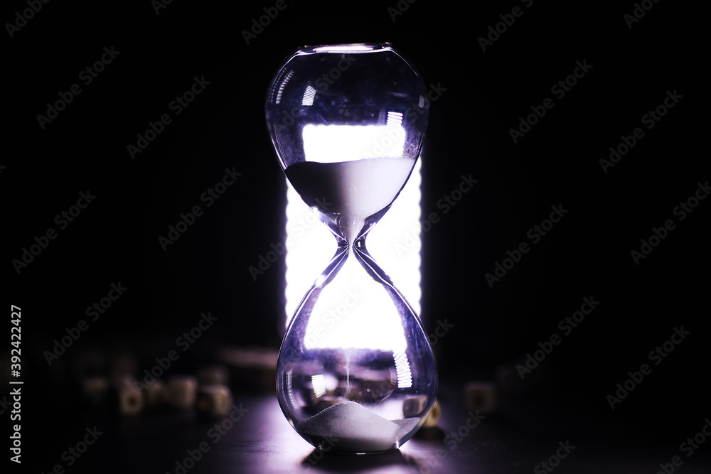 Sand running through the bulbs of an hourglass measuring the passing ...