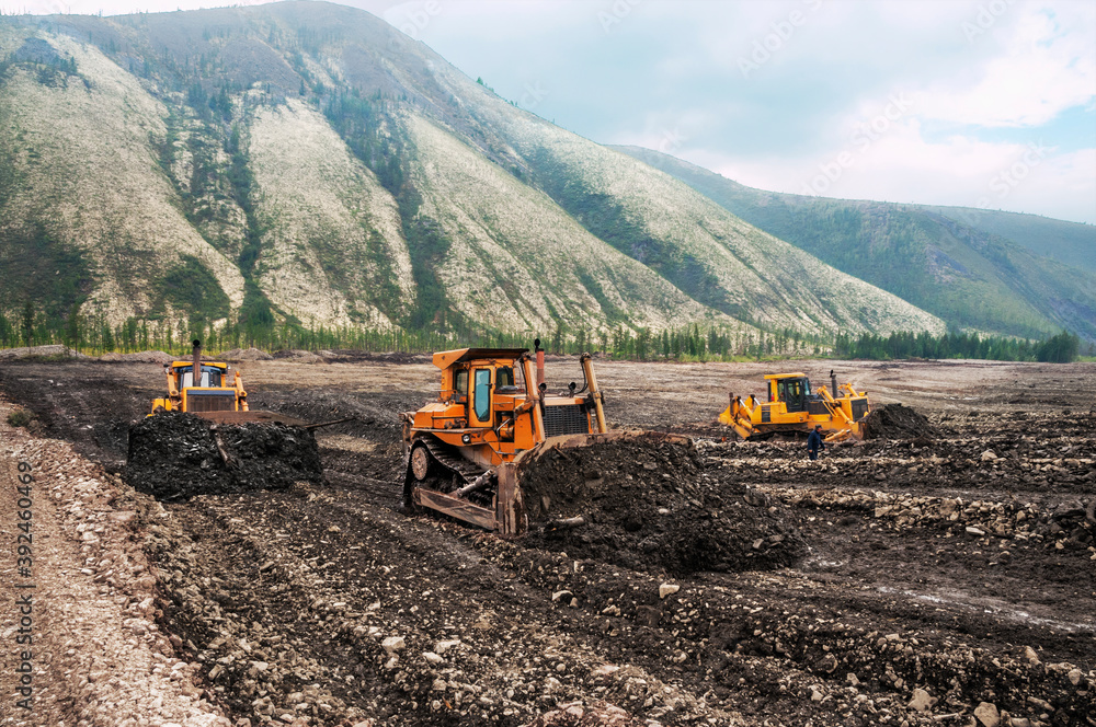 Bulldozers at work. Mining. Bulldozers cut the topsoil in a mountainous ...