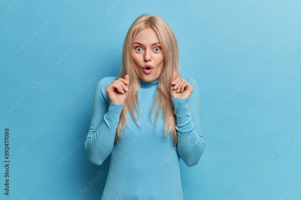 Stunned blonde young pretty European woman stands impressed looks with ...
