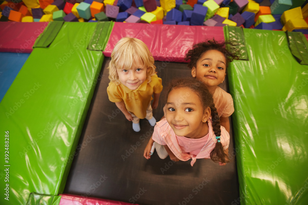Portrait of group of children looking at camera while jumping on ...