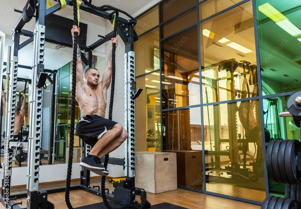 Young muscular fitness man training abdominal muscles while hanging on ...