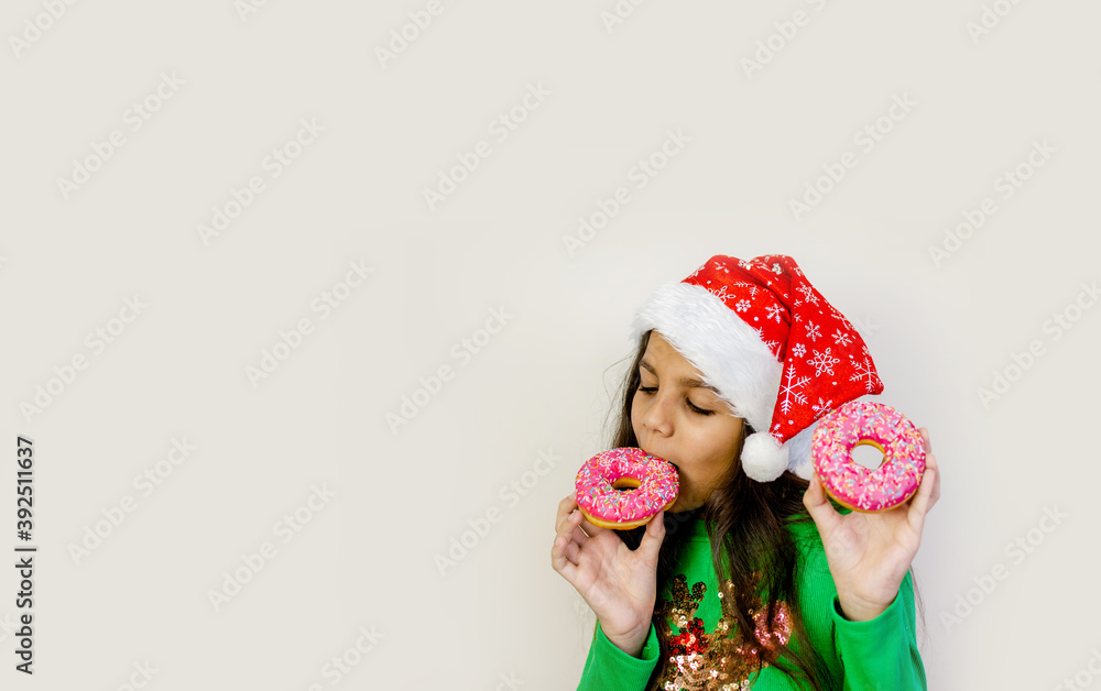 Cute dak hair girl in santa hat smiling, having fun and tasting two ...