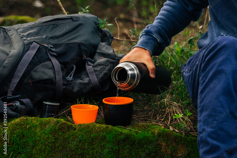 Drinking tea during hike. Man hand pouring hot tea from black thermos ...