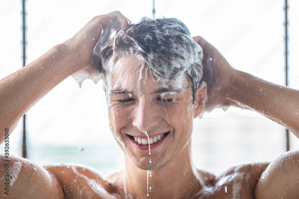 Handsome young male model washing hair with shampoo Stock Photo | Adobe ...