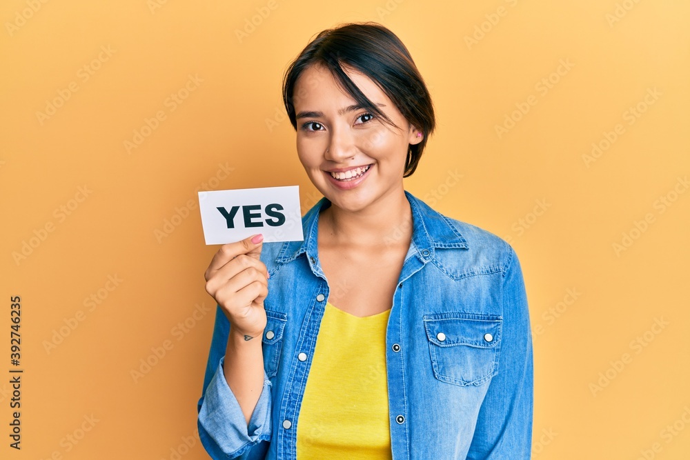 Beautiful young woman with short hair holding yes reminder looking ...