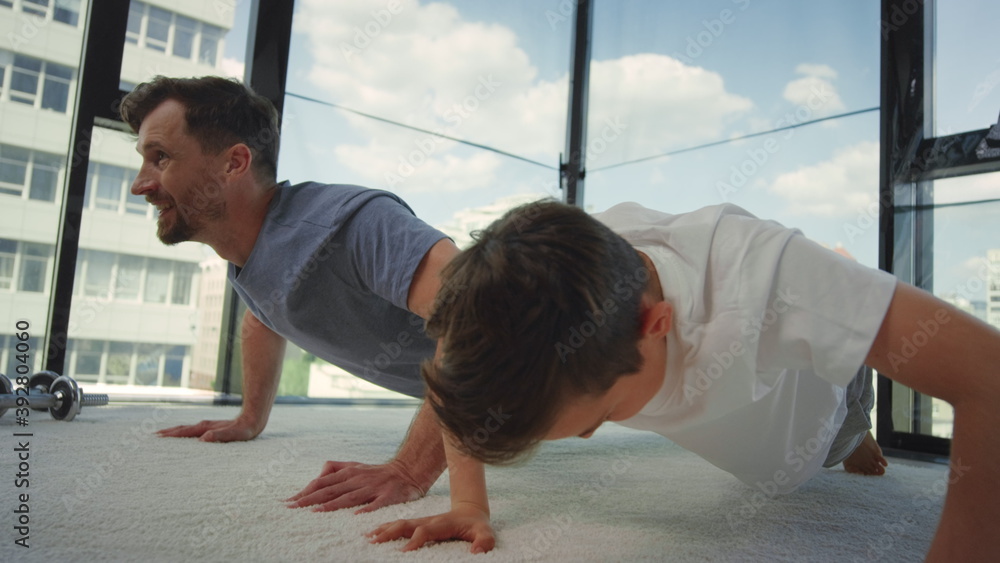 Energy man and boy pushing up at home. Father and son having workout ...