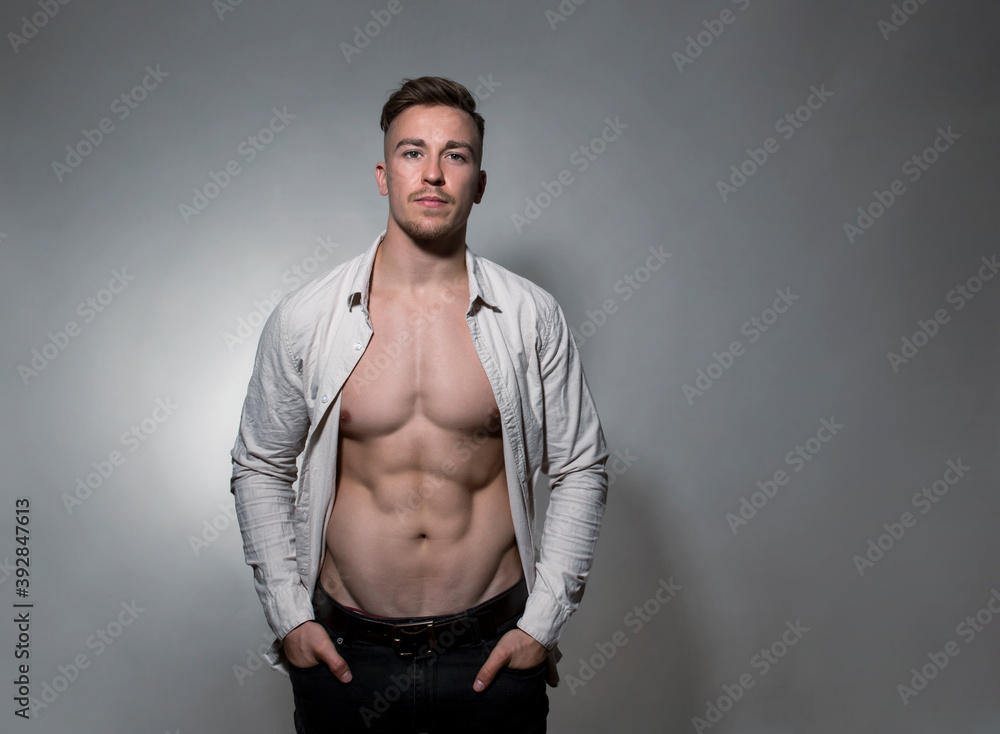 Fit Bodybuilder with defined muscles on grey background wearing dress ...