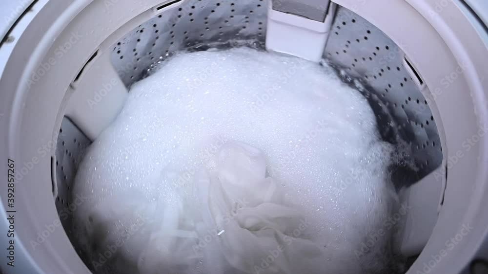 Clothes in a washing machine at close range running in a spin Stock ビデオ ...