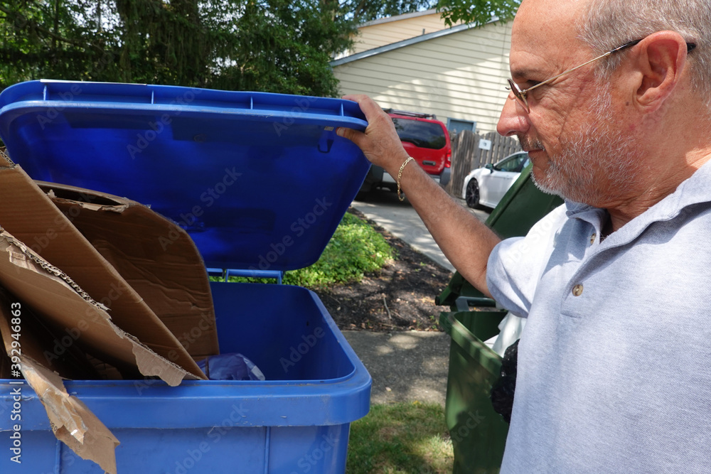 Male Caucasian senior citizen holding open the lid of a recycling trash ...