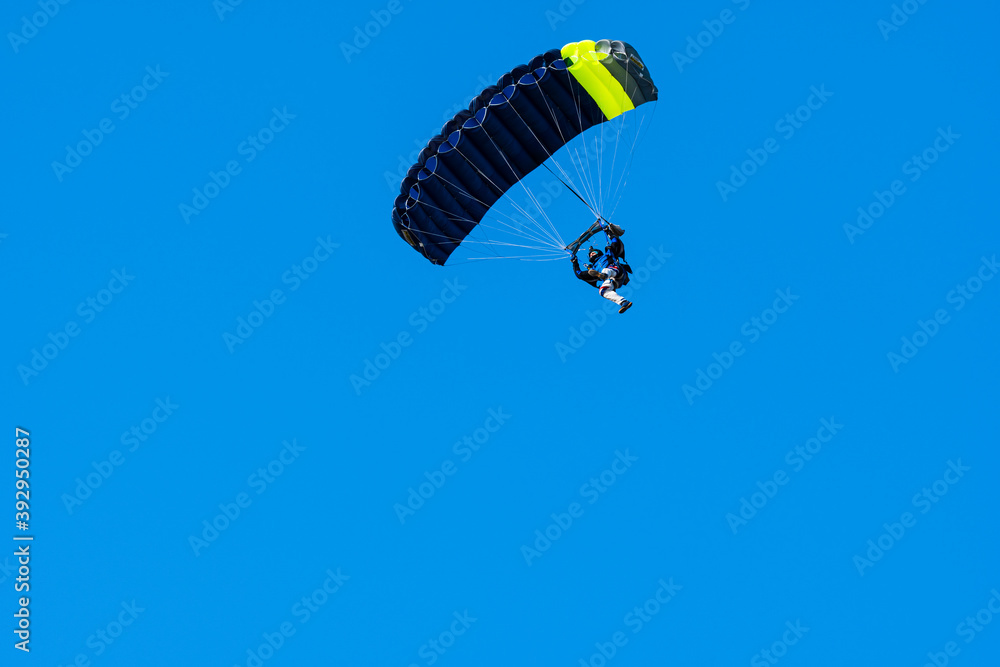 Tandem parachute jump. Silhouette of skydiver flying in blue clear sky ...