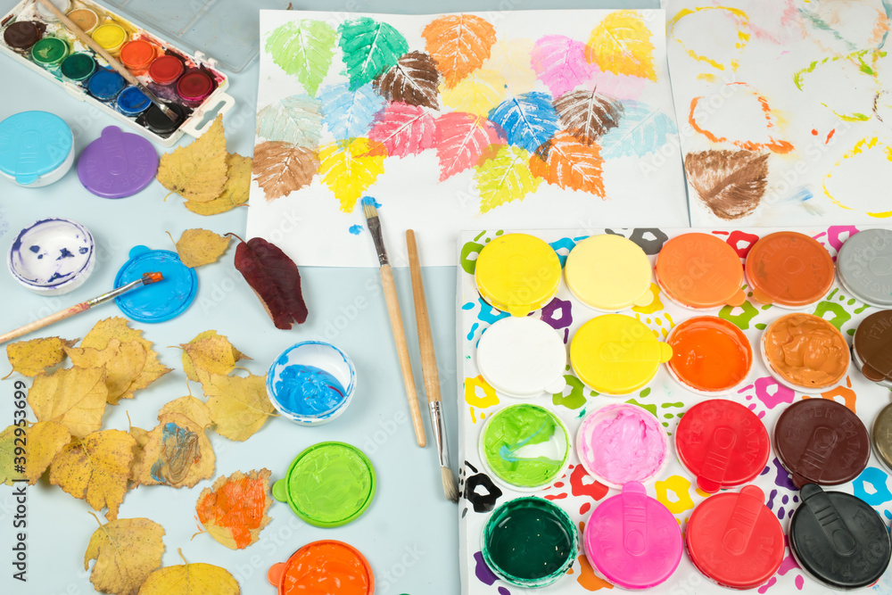 Finger paints and watercolors on the child table. Painted autumn tree ...