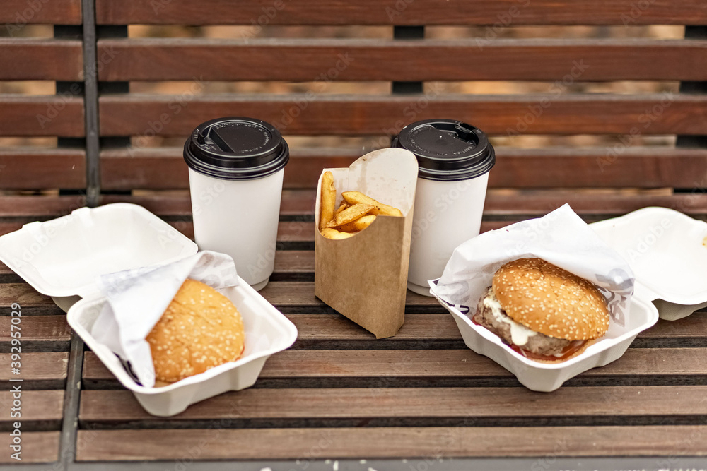 Fast food. Paper cups with coffee, hamburger boxes and fries on a park ...
