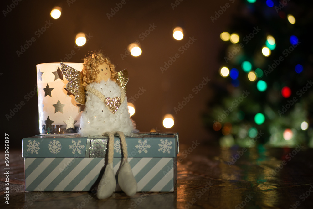 An angel sits on a gift box. Christmas tree decorations in the room at ...