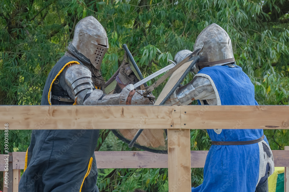 Two foot warriors in heavy medieval armor fight in the arena. Armed ...
