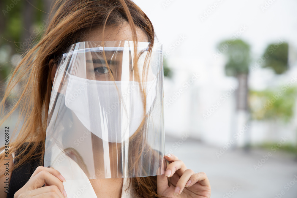 woman wearing face mask and face shield, observing new normal social ...