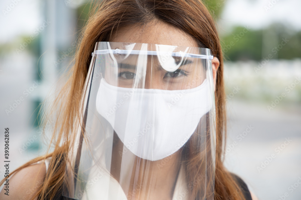 woman wearing face mask and face shield, observing new normal social ...